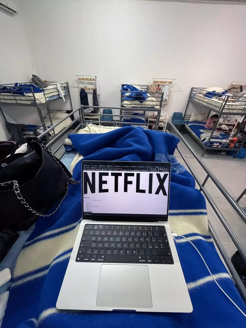 Zdjęcie laptopa z podniesioną witryną Netflix, jak sfotografowany ze szczytu łóżka piętrowego w obozie dla uchodźców z wojny na Ukrainie