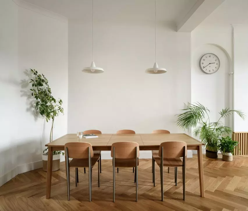 Table à manger et chaises en bois entourées de plantes sur un parquet à chevrons dans l'appartement d'Édimbourg par Luke McClelland