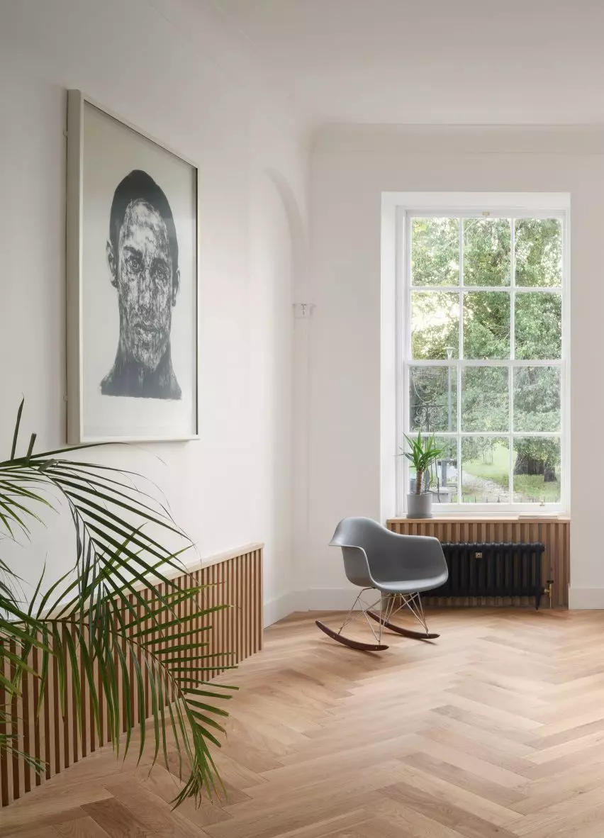 Salon lambrissé de chêne avec parquet et fauteuil à bascule gris à côté d'un portrait d'art de l'appartement Leith