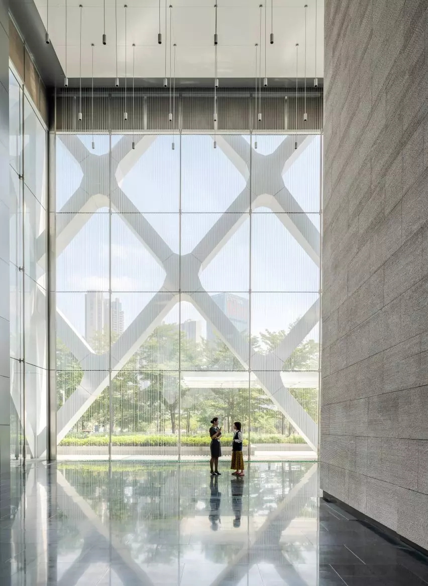 Vestíbulo do edificio do banco de Shenzhen de SOM con paredes revestidas de pedra nun lado e unha cortina de choiva en primeiro plano e unha estrutura de diagrama exterior visible detrás dela