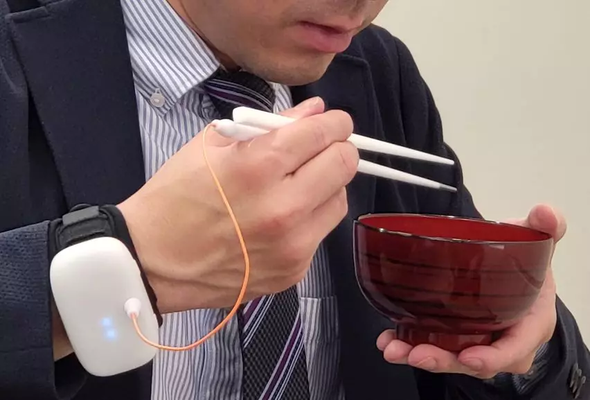 Um homem comendo missô com pauzinhos de ajuste de sabor