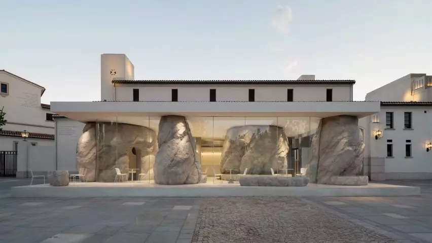 L'extérieur du Zolaism Cafe avec des projecteurs suspendus illuminant des colonnes en béton ressemblant à des rochers