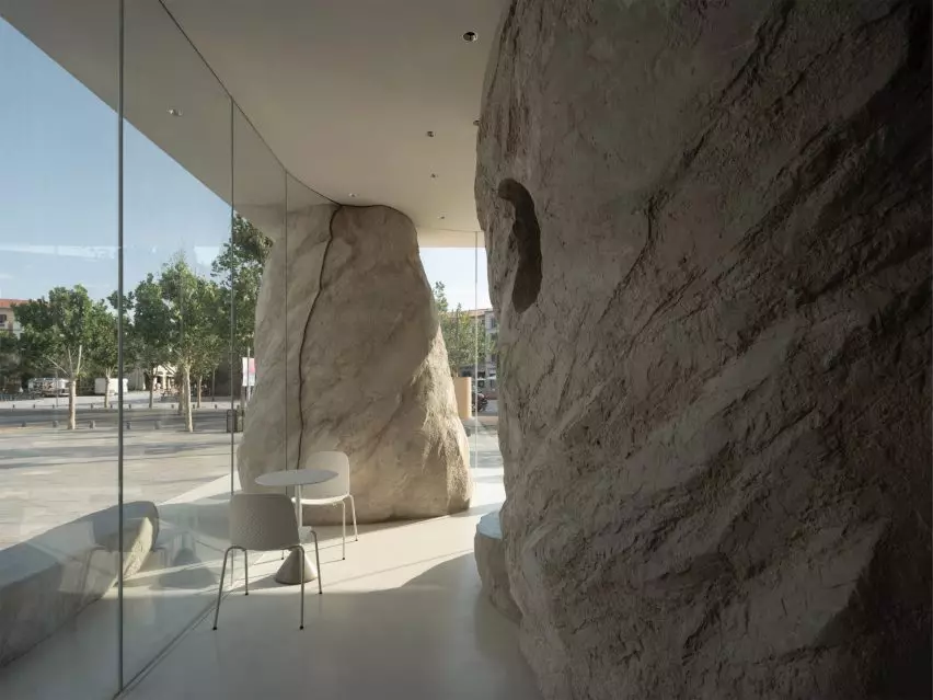 Table et chaises blanches dans le Zolaism Café à côté d'un mur de verre et entouré de colonnes en forme de rocher