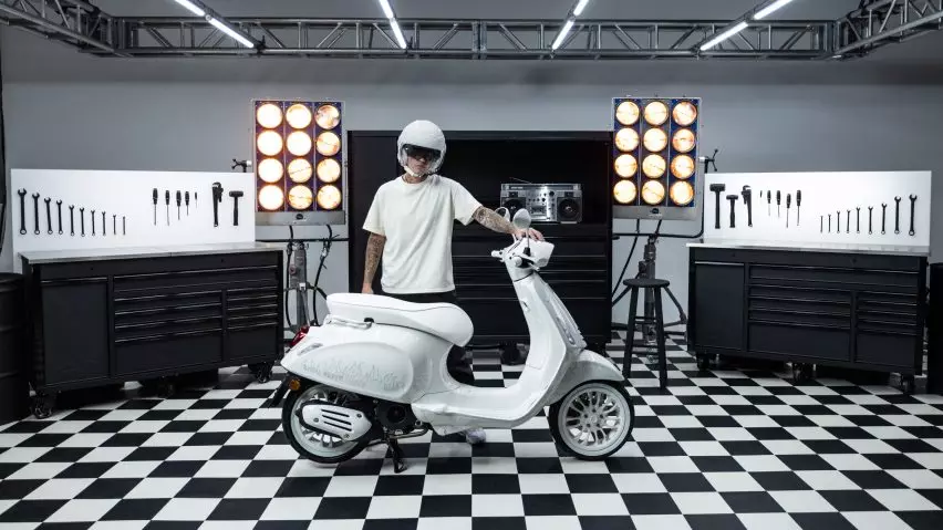 Justin Bieber i en hvit hjelm holder en sparkesykkel han designet for Vespa