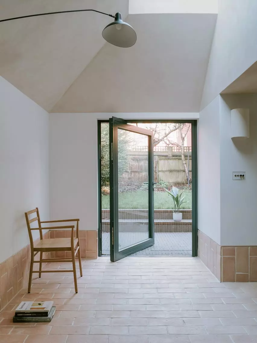 Puerta pivotante de vidrio junto a una silla en el interior de una casa por Studio McW