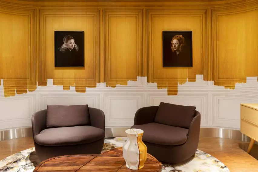 Mga brown armchair sa harap ng puti at dilaw na pininturahan na pader na may Dutch master replicas sa airport lounge na idinisenyo ni Marcel Wanders