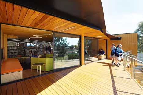 Puilla verhoiltu koulukirjasto, jonka Branch Studio Architects on laajentanut puiden latvoihin