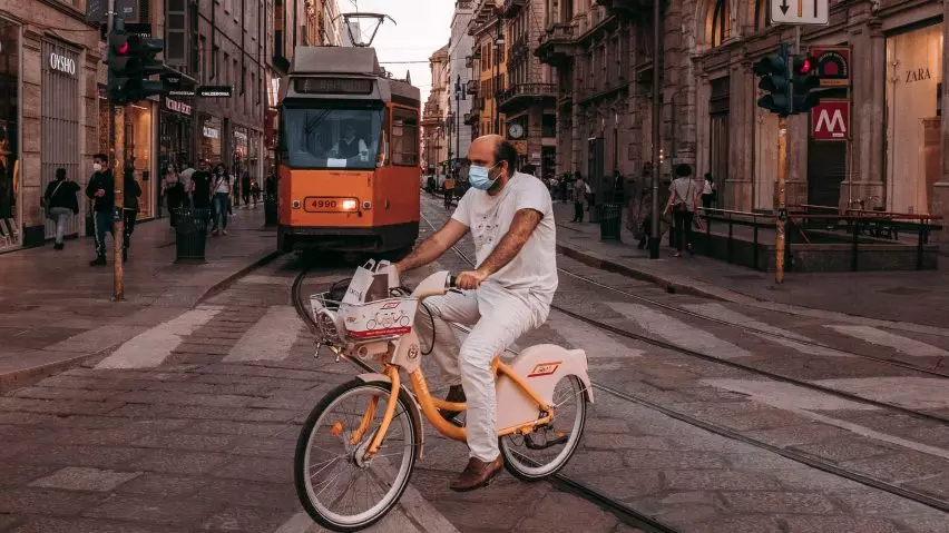 Viro biciklanta antaŭ tramo en Milano, ilustrante novaĵo pri la laŭplana bicikla reto Cambio en Milano