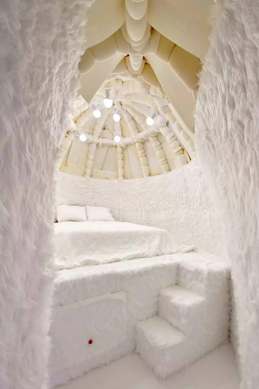 Brendësia e dhomës së gjumit dimëror nga Takk me tavan me kube të mbuluar me shkumë dhe shtrat në një platformë të ngritur të mbuluar nga qilim i bardhë me gëzof
