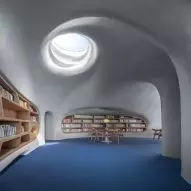 Një bibliotekë betoni e ndriçuar nga një çati xhami