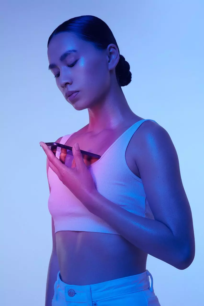 Женщина держит светящийся телефон на груди