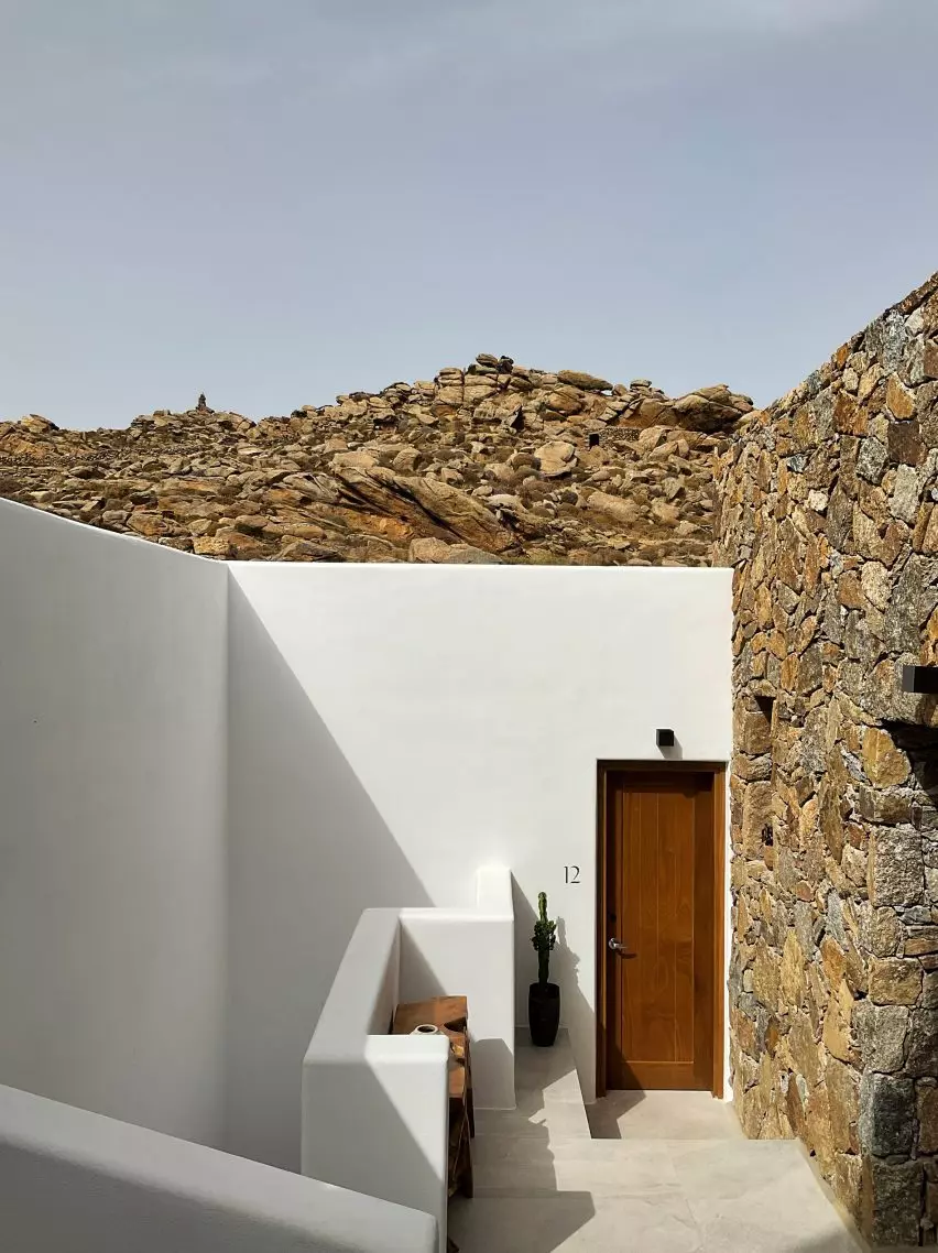 Entrada ao Mykonos Wellness Resort cunha parede branca e outra de pedra que se funde co outeiro