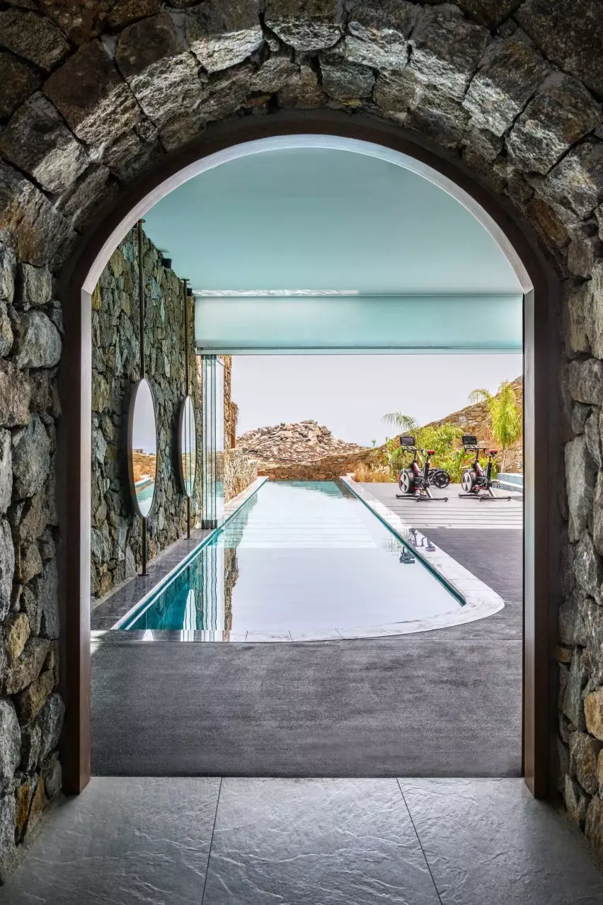 Vista a través do arco de pedra no Mykonos Wellness Resort en bicicletas estáticas ao carón dunha piscina