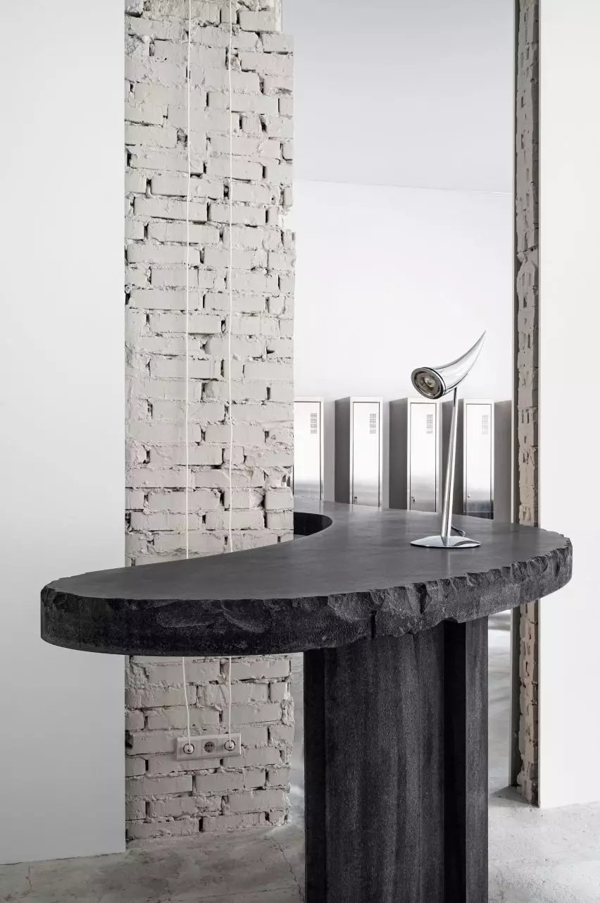 Zakrivljeni betonski sto sa hromiranim svetlom u studiju 6:19