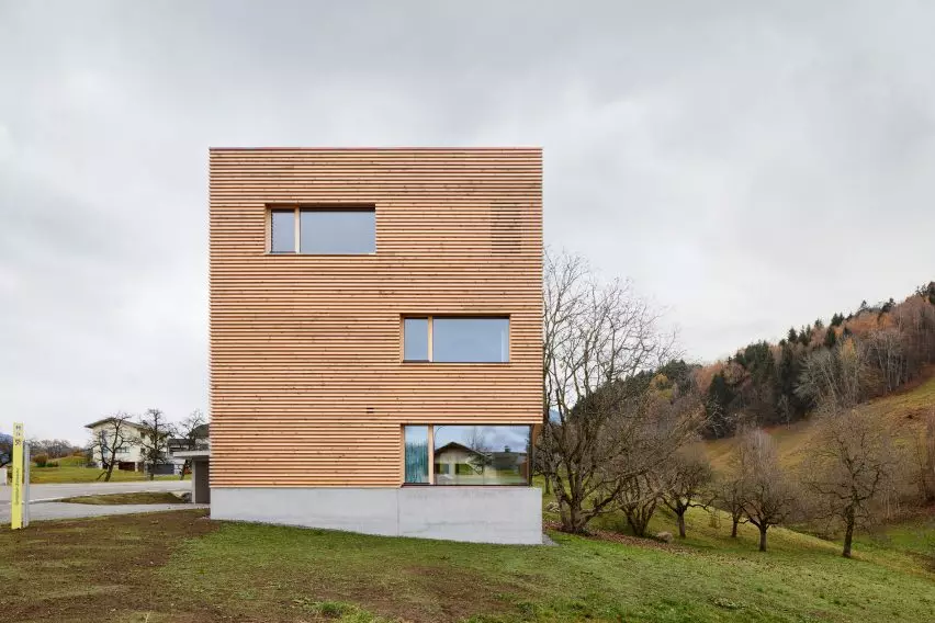 E quadratesch Holz gekleet Haus mat enger konkreter Basis