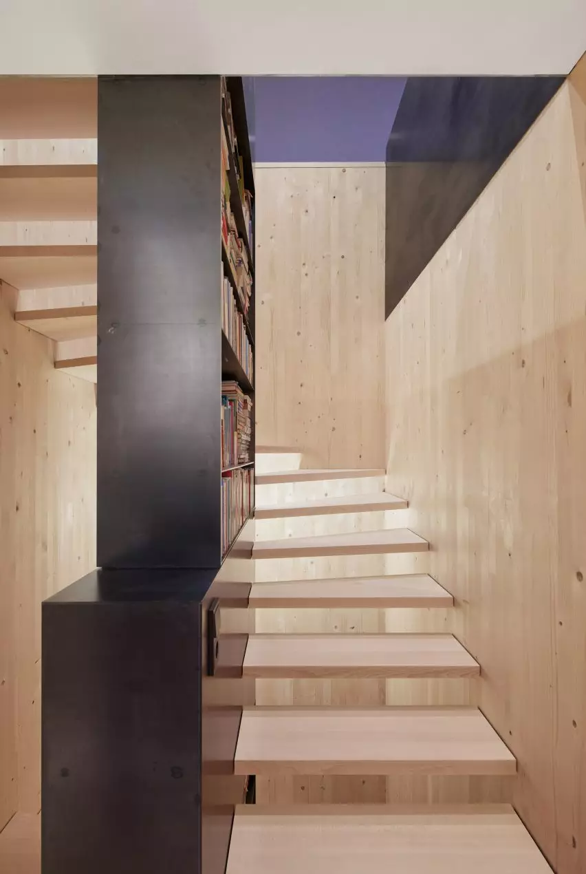 O scară din molid cu treaptă deschisă, cu o bibliotecă din oțel negru